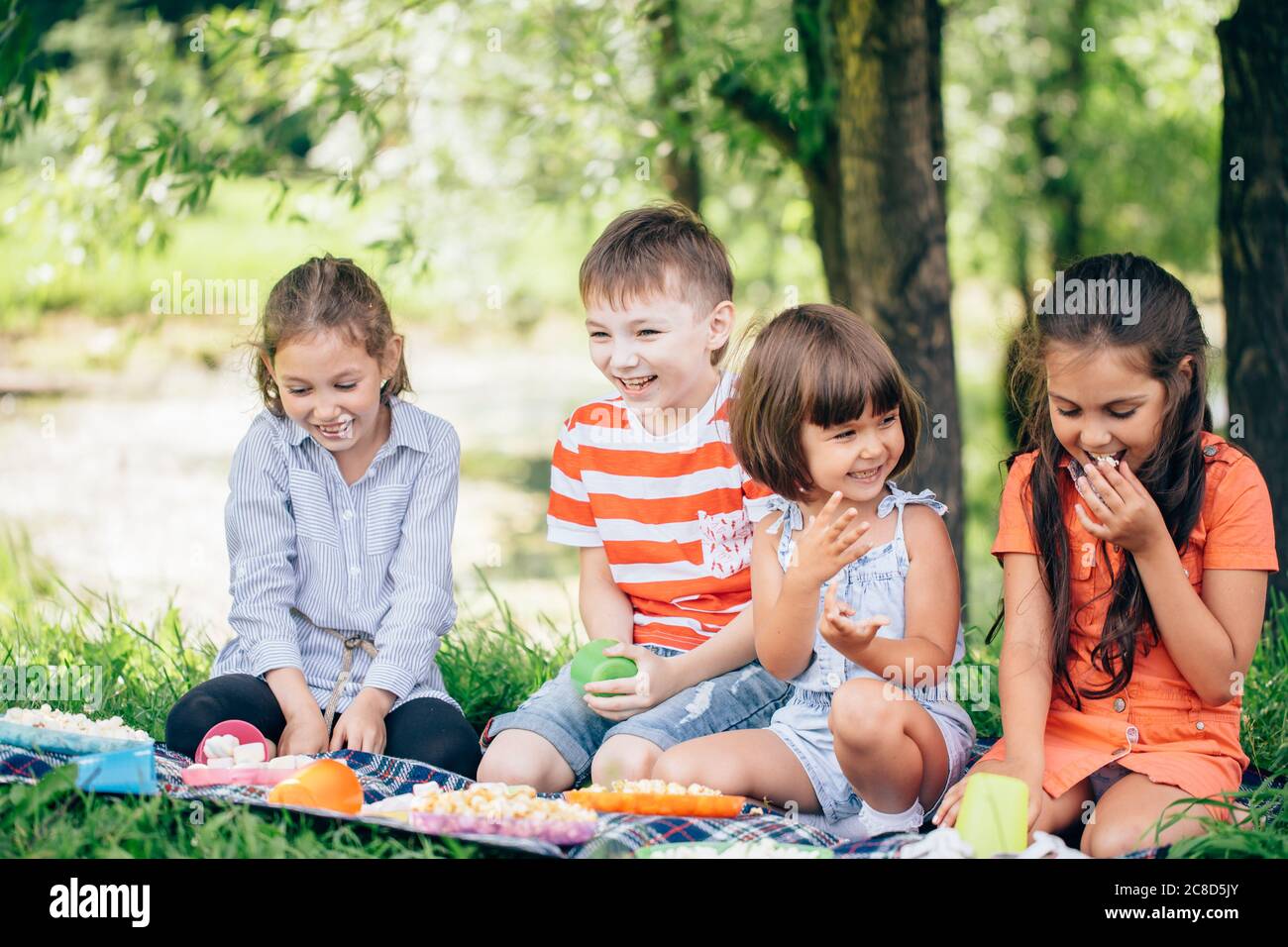 Little children eating lunch outdoors. Kids with picnic basket in ...