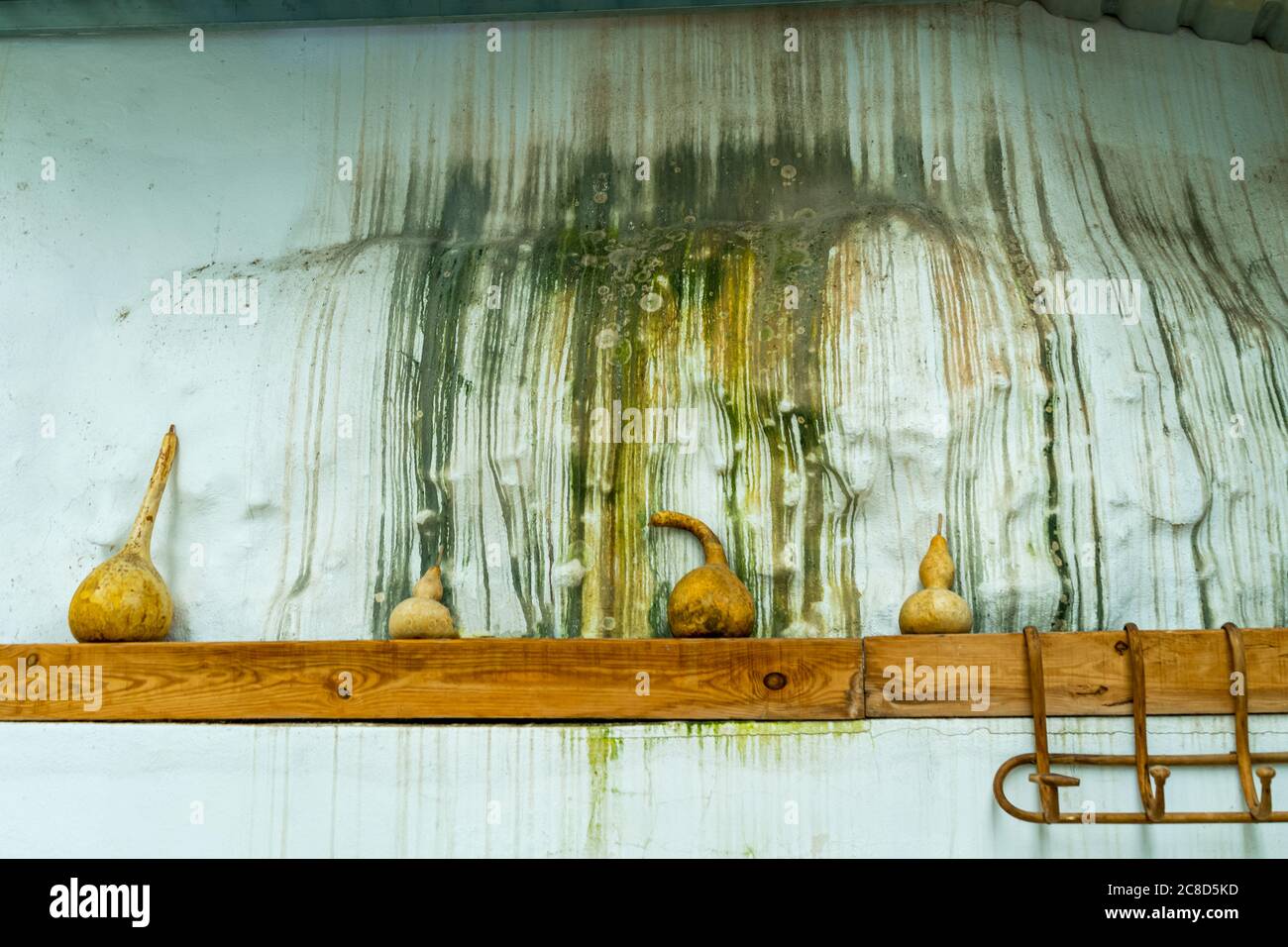 Old damp stained rock wall with a porch decorated with dried gourds ...