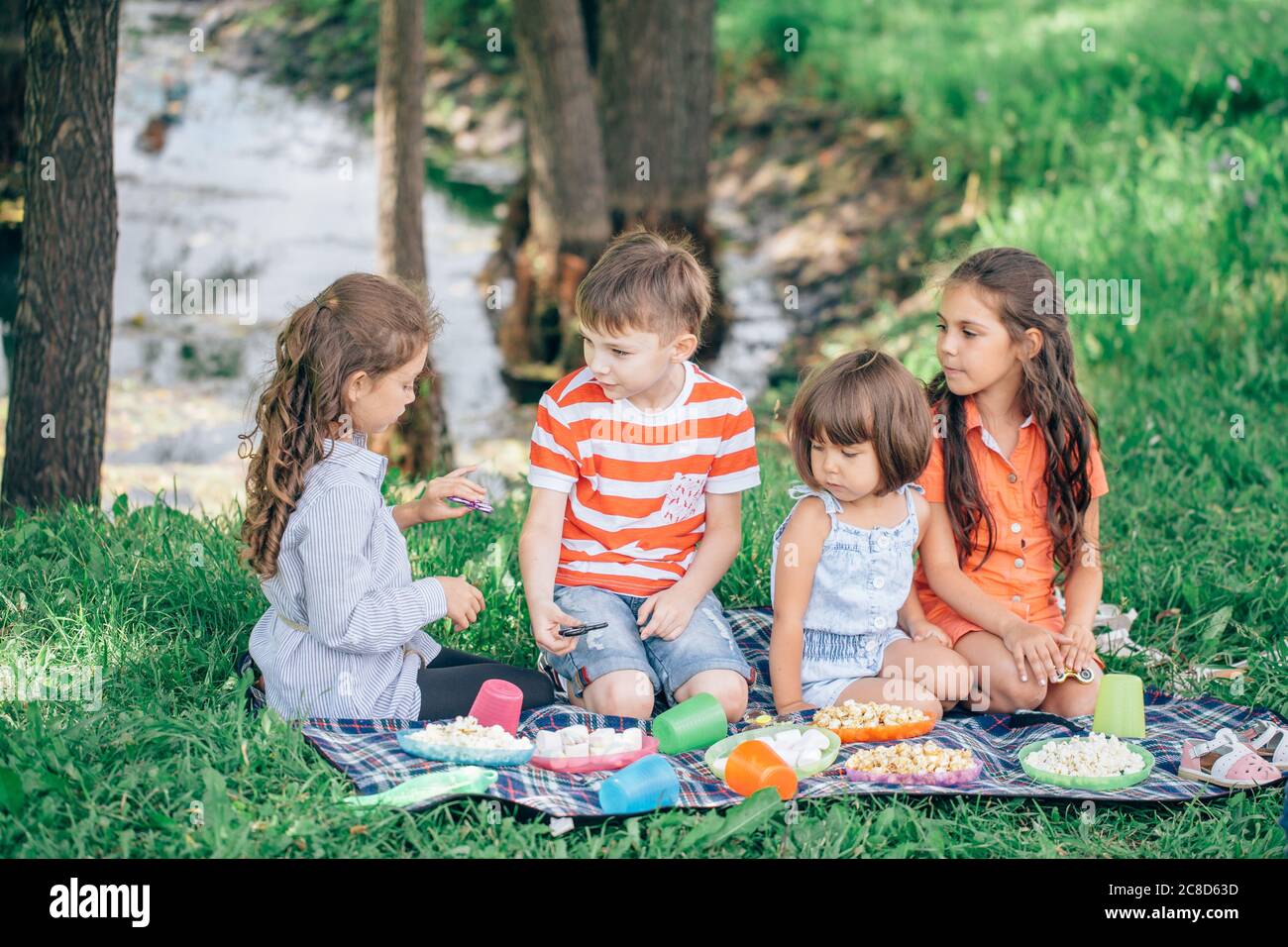 Little children eating lunch outdoors. Kids with picnic basket in ...