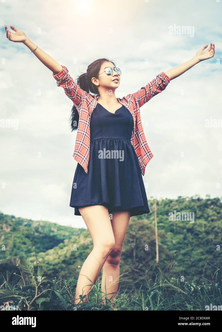 Happy woman in green field and mountain background Stock Photo - Alamy