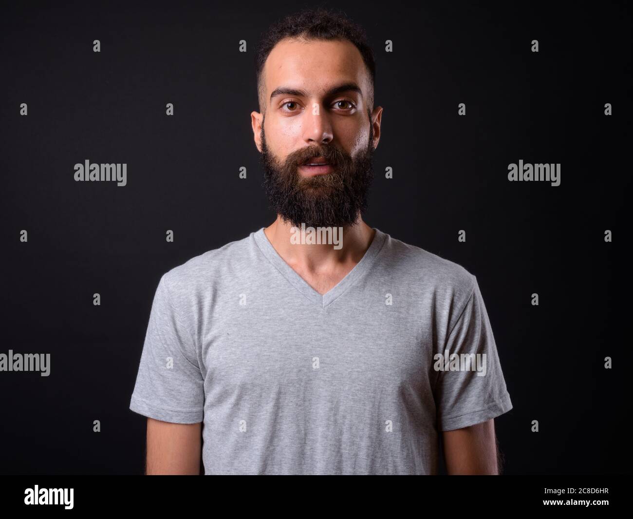 Young handsome Persian man with dreadlocks against black background ...