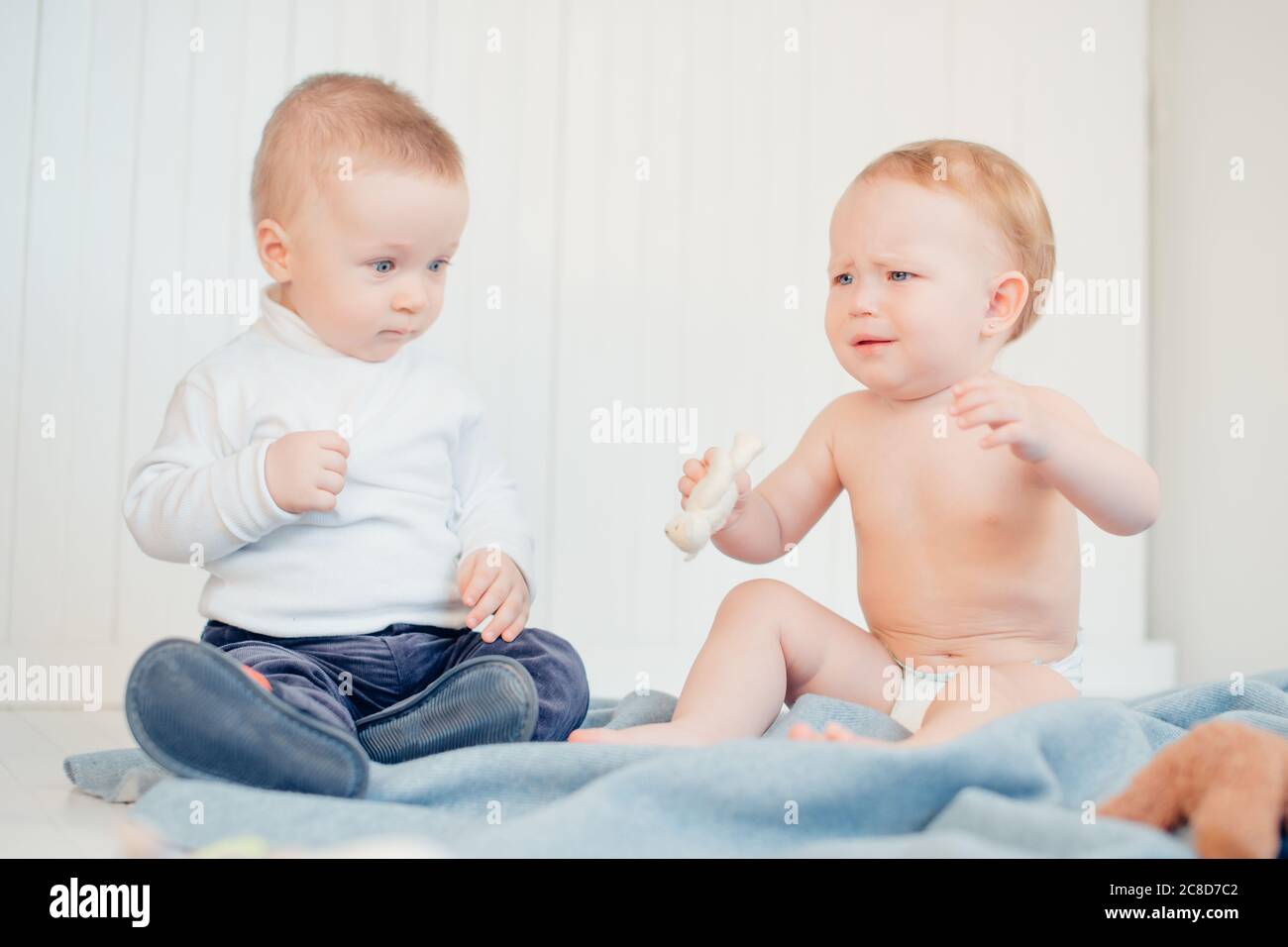 Side view of two babies playing on bed Stock Photo - Alamy