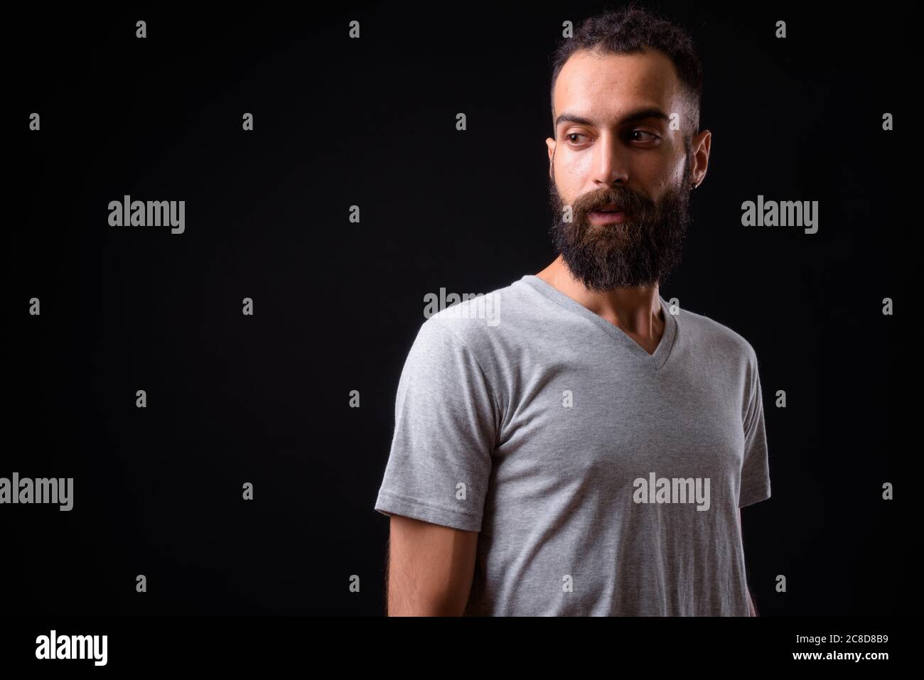 Young handsome Persian man with dreadlocks against black background ...