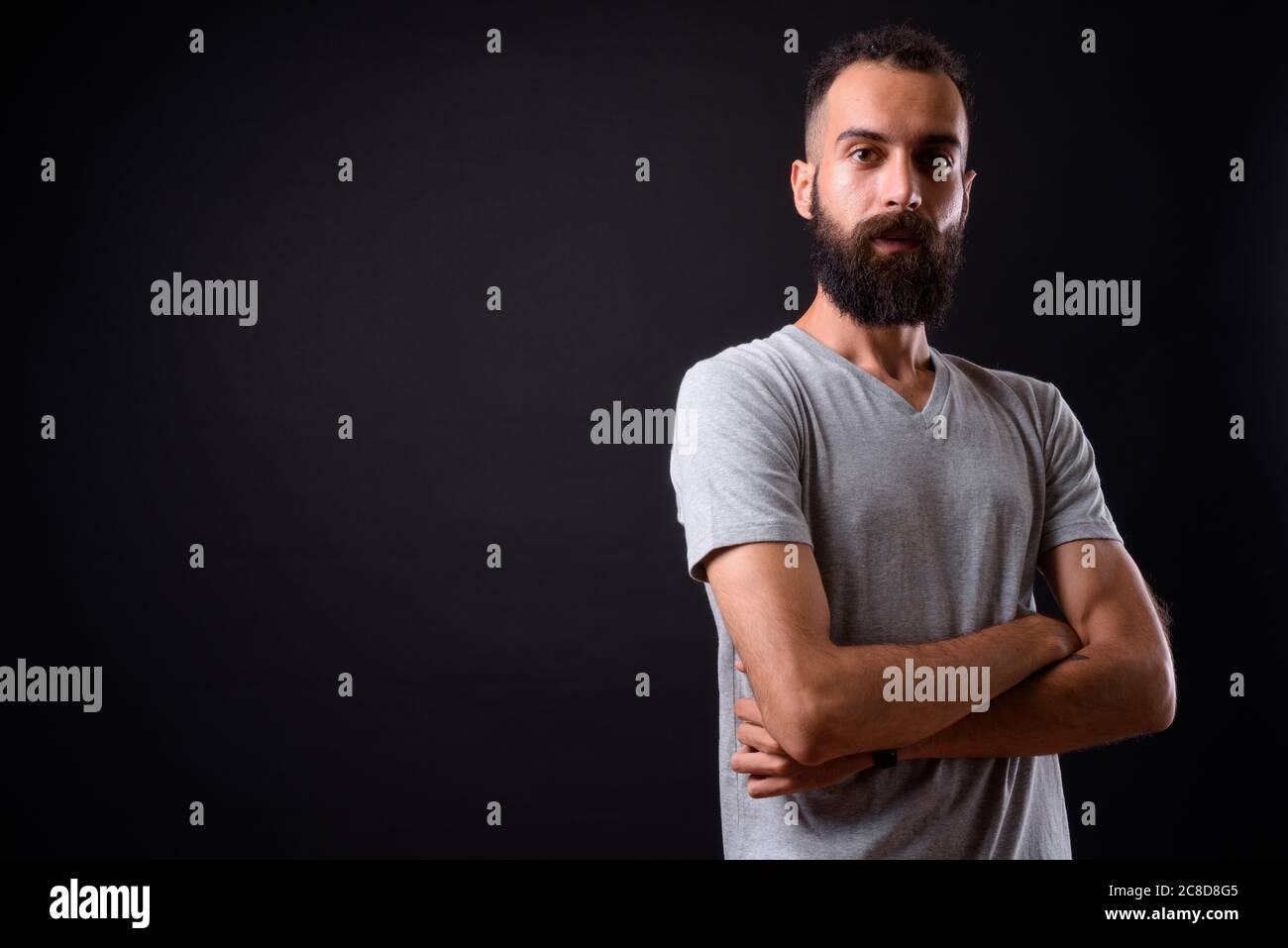 Young handsome Persian man with dreadlocks against black background ...