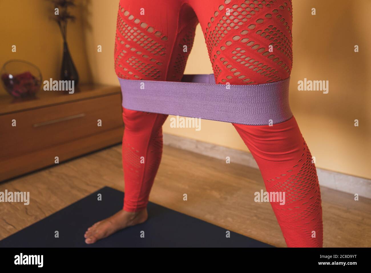 Legs of an unrecognizable young girl in red sportswear stretching with ...