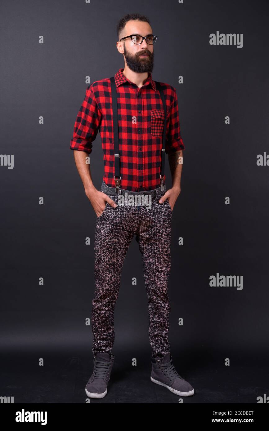 Young handsome Persian man with dreadlocks against black background ...