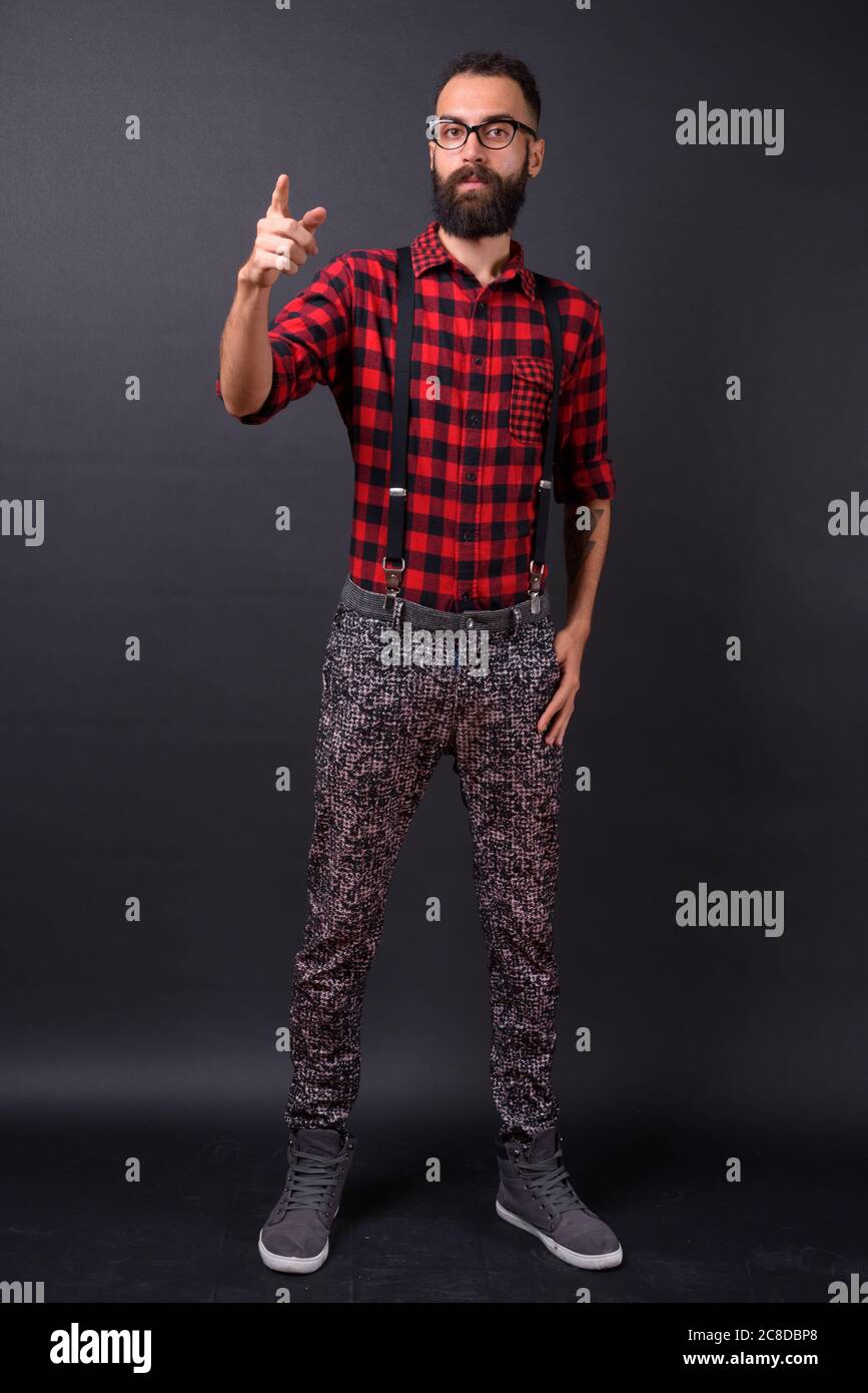 Young handsome Persian man with dreadlocks against black background ...
