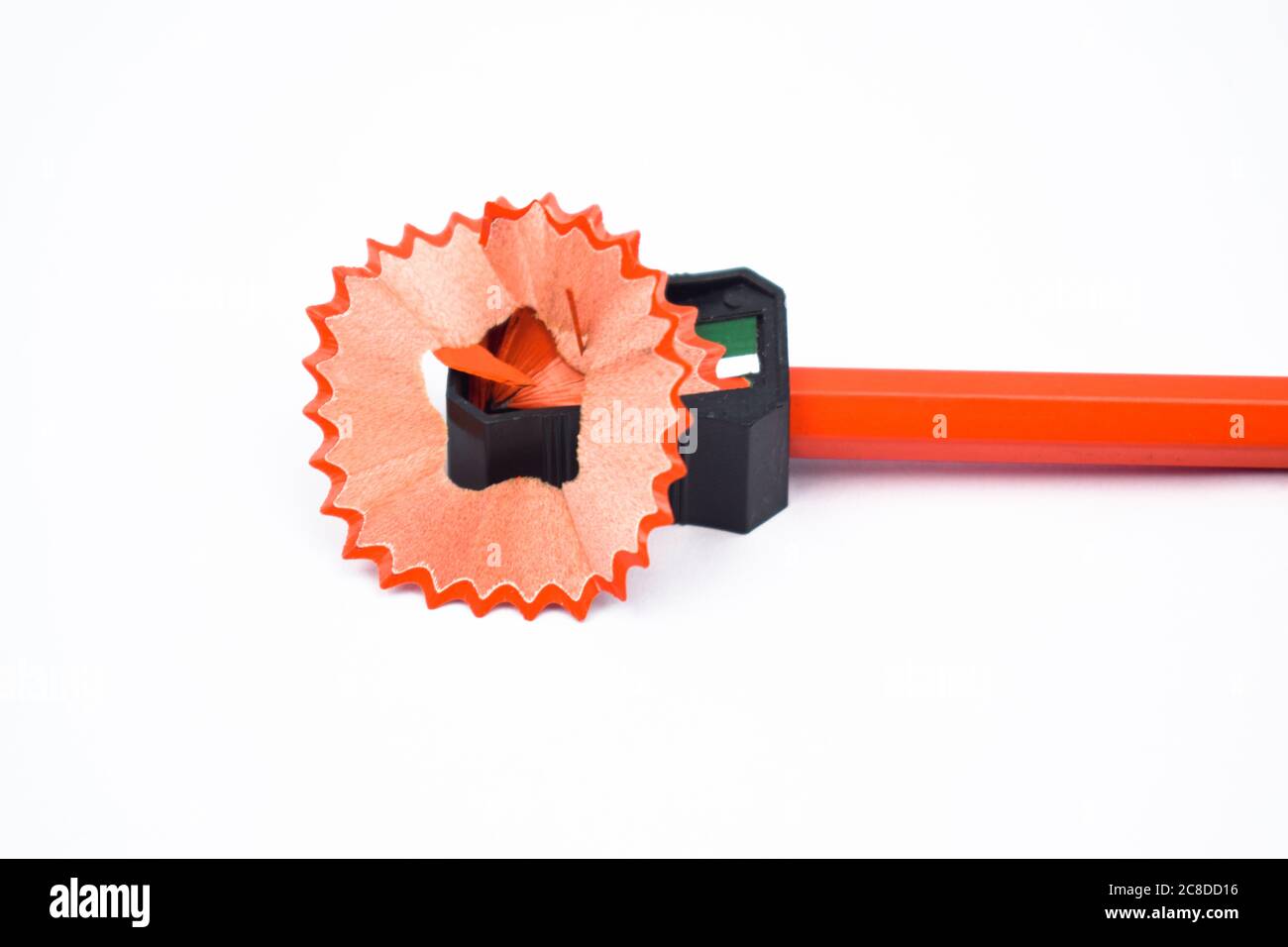 Sharpening a orange color wood pencil crayon with a black color plastic ...