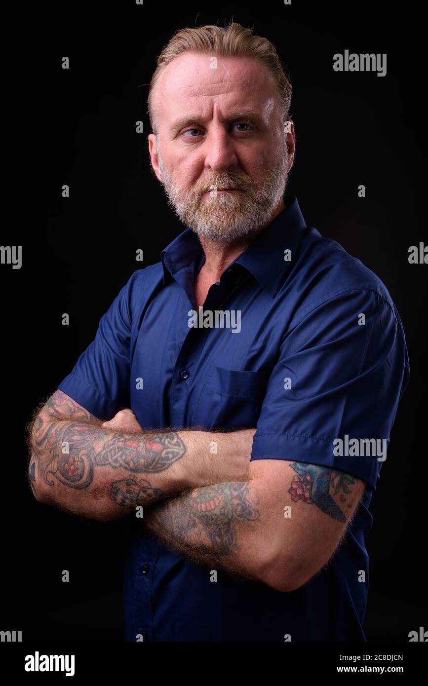 Mature Handsome Bearded Man With Blond Hair Against Black Background