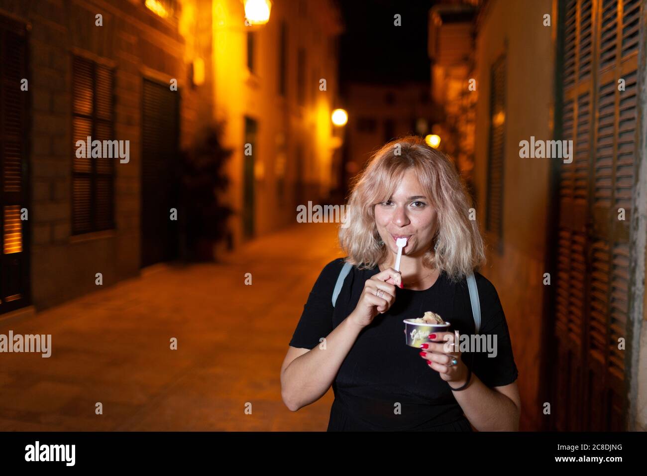 Blonde girl eating gelato in the streets of Alcudia old town, Mallorca ...