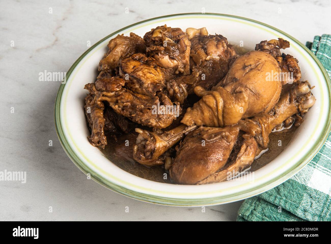 A serving of Filipino-style chicken adobo dish in a bowl with green ...