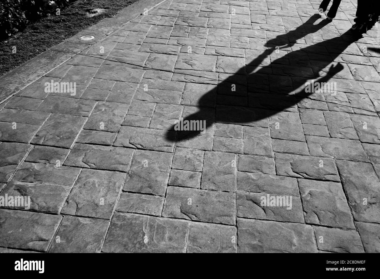 Beautiful long shadows on a cobbled path of a father and his little ...