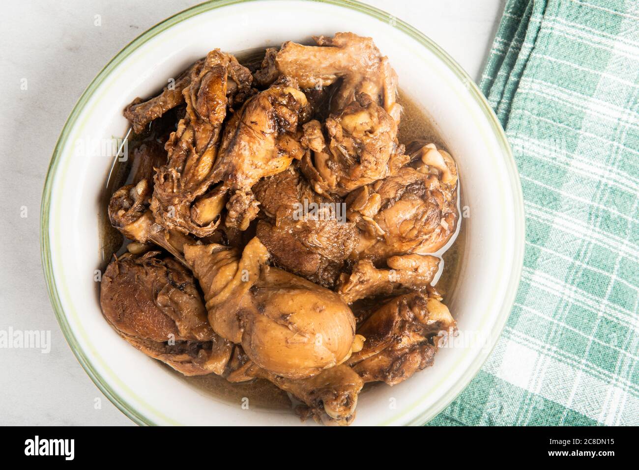 A serving of Filipino-style chicken adobo dish in a bowl with green ...
