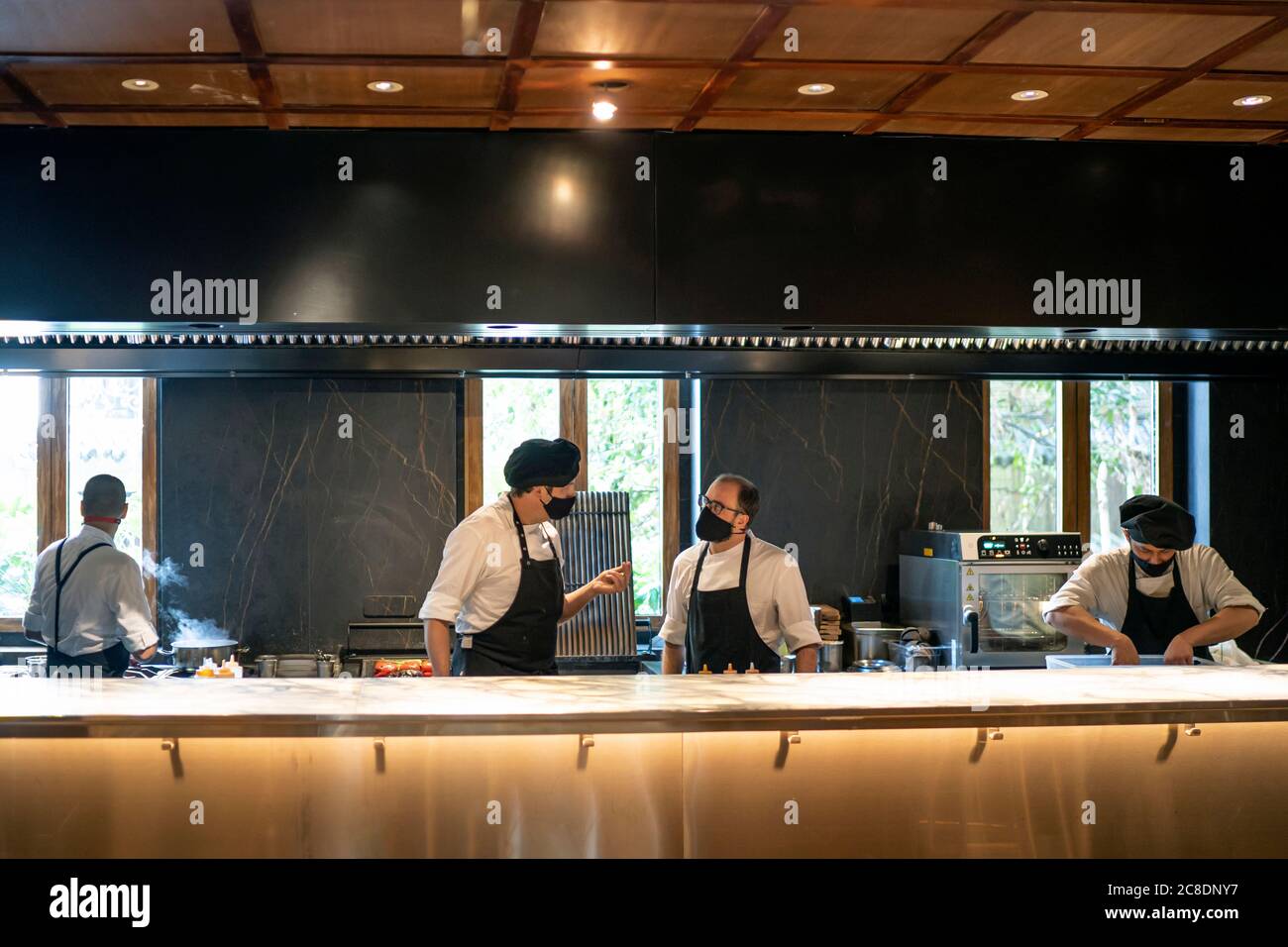 Chefs wearing protective face masks working together in restaurant ...