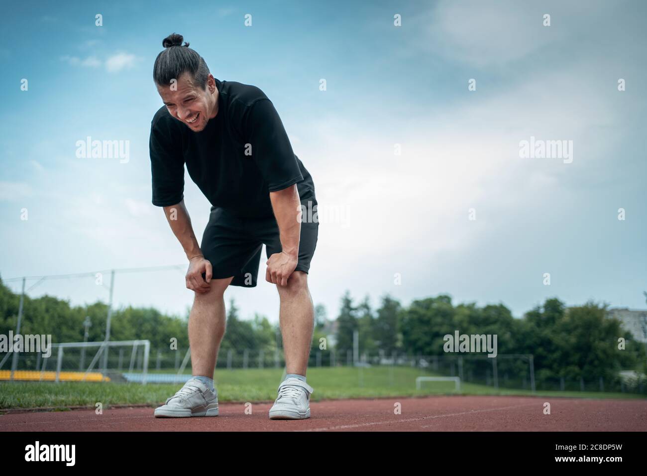 exhausted athlete resting on track after running or workout exercising ...