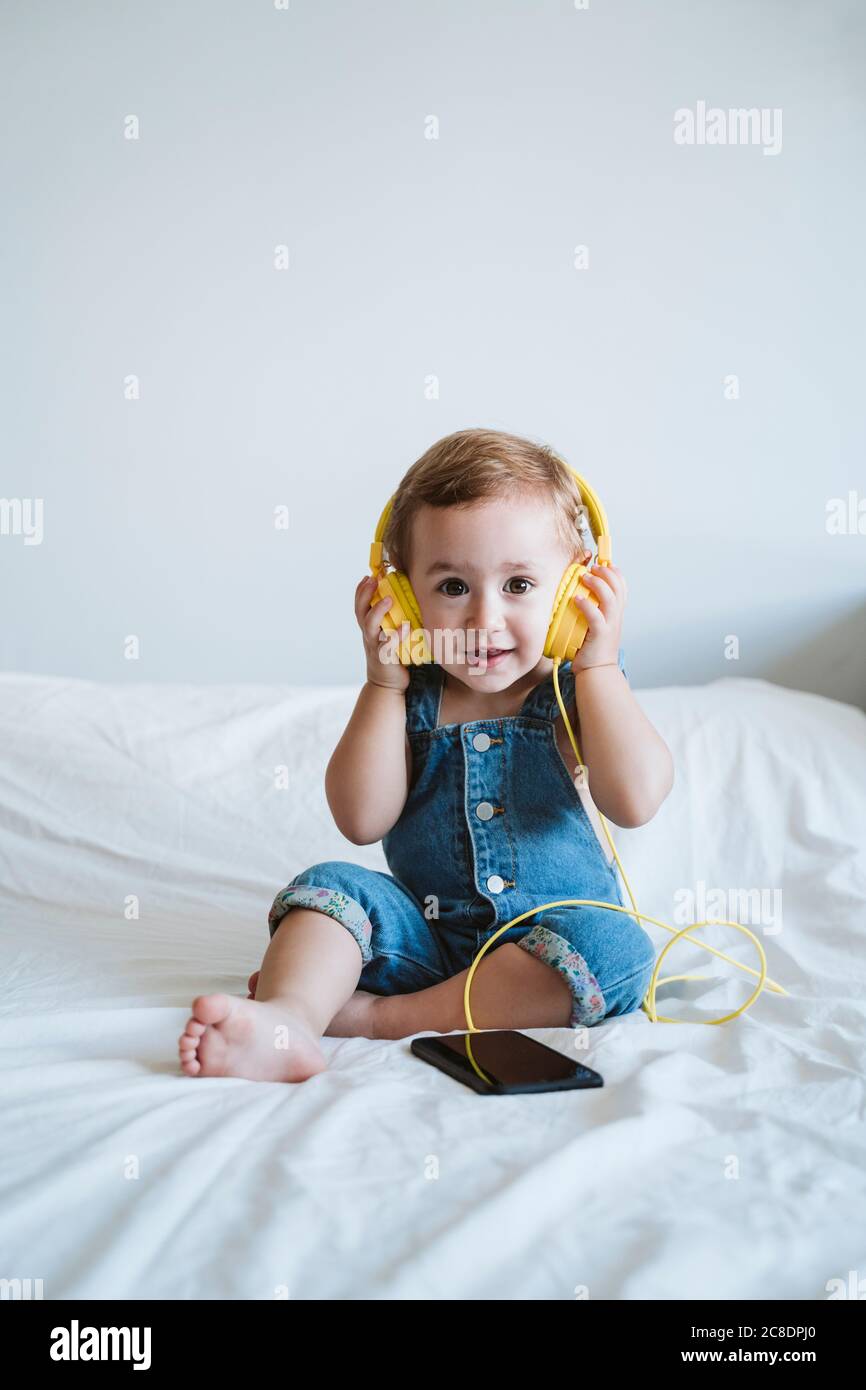Baby girl at home listening to music on bed Stock Photo - Alamy