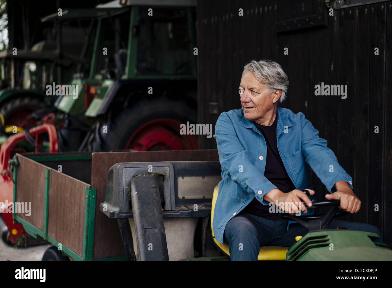 Senior man driving tractor with trailer on a farm Stock Photo - Alamy