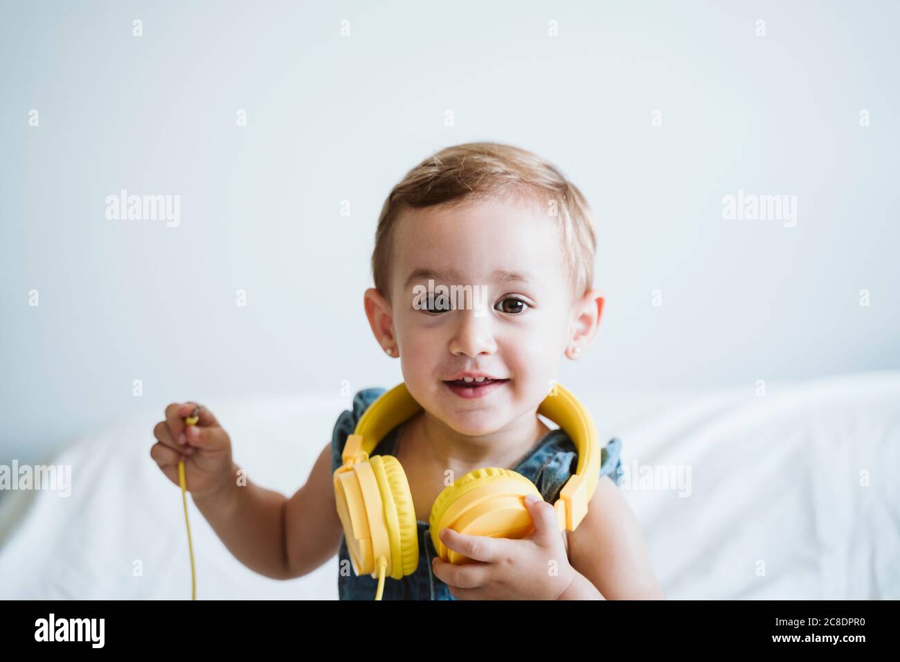 Baby girl at home listening to music on bed Stock Photo - Alamy