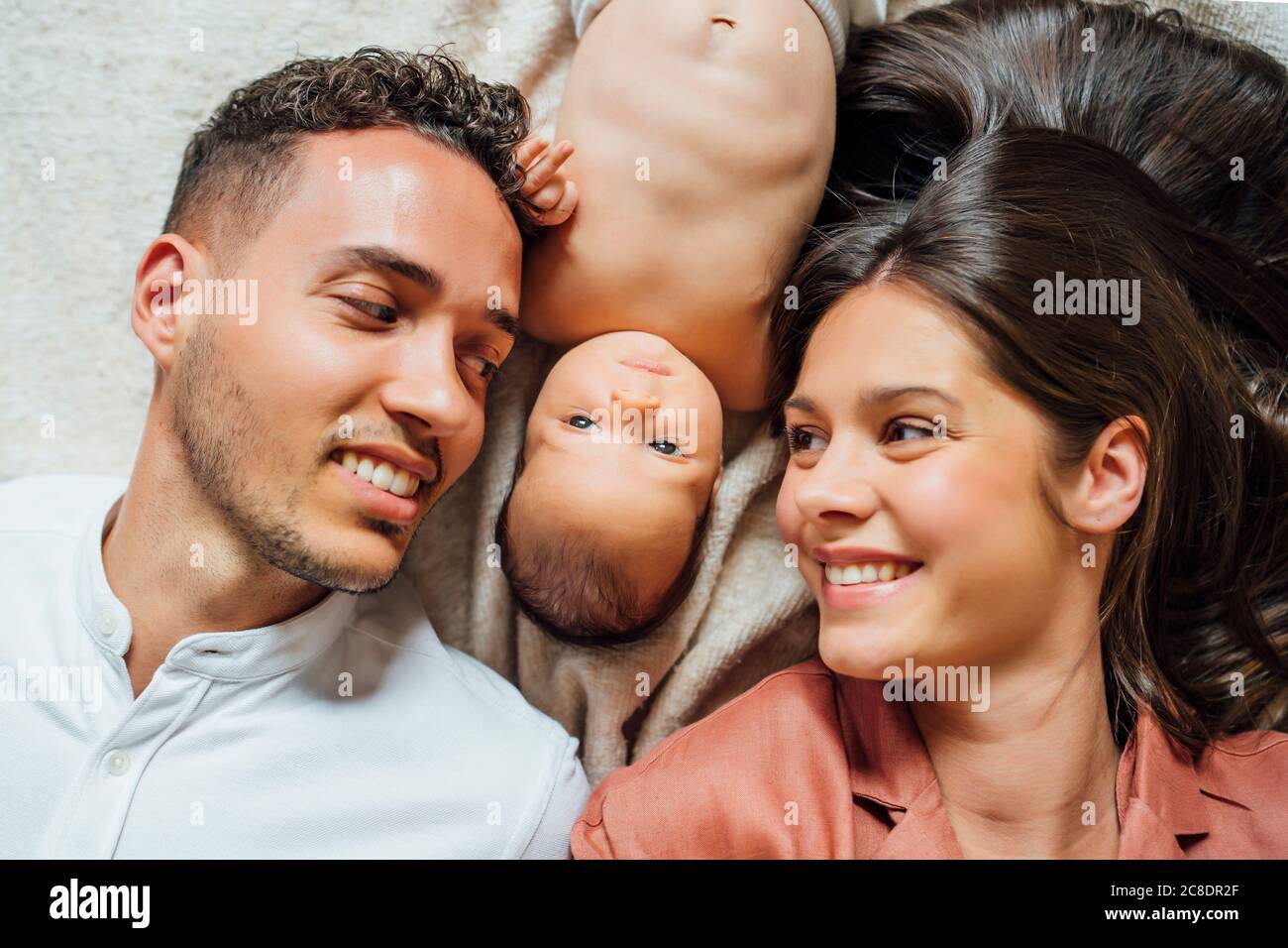 Happy parents lying with baby boy on bed Stock Photo - Alamy