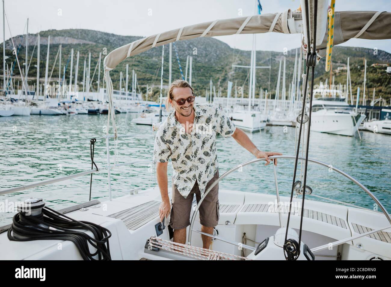 Happy sailor undocking sailboat at harbor Stock Photo - Alamy