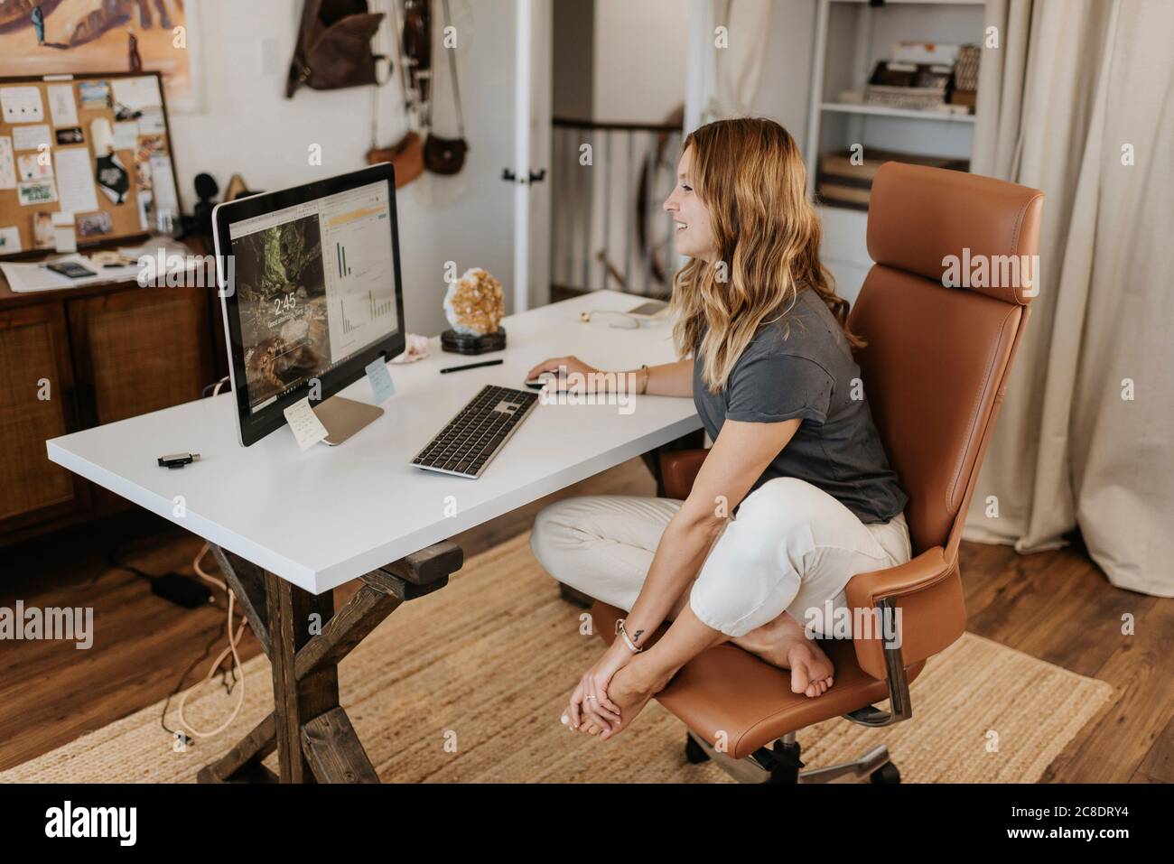 Woman using computer on desk at home Stock Photo - Alamy