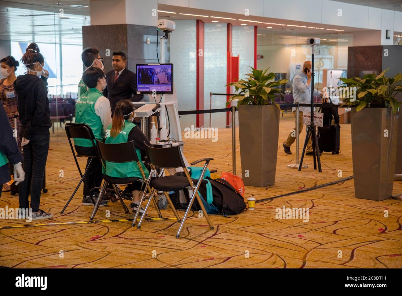 SINGAPORE - JULY 21. 2020: Changi airport staff sit behind a thermal ...