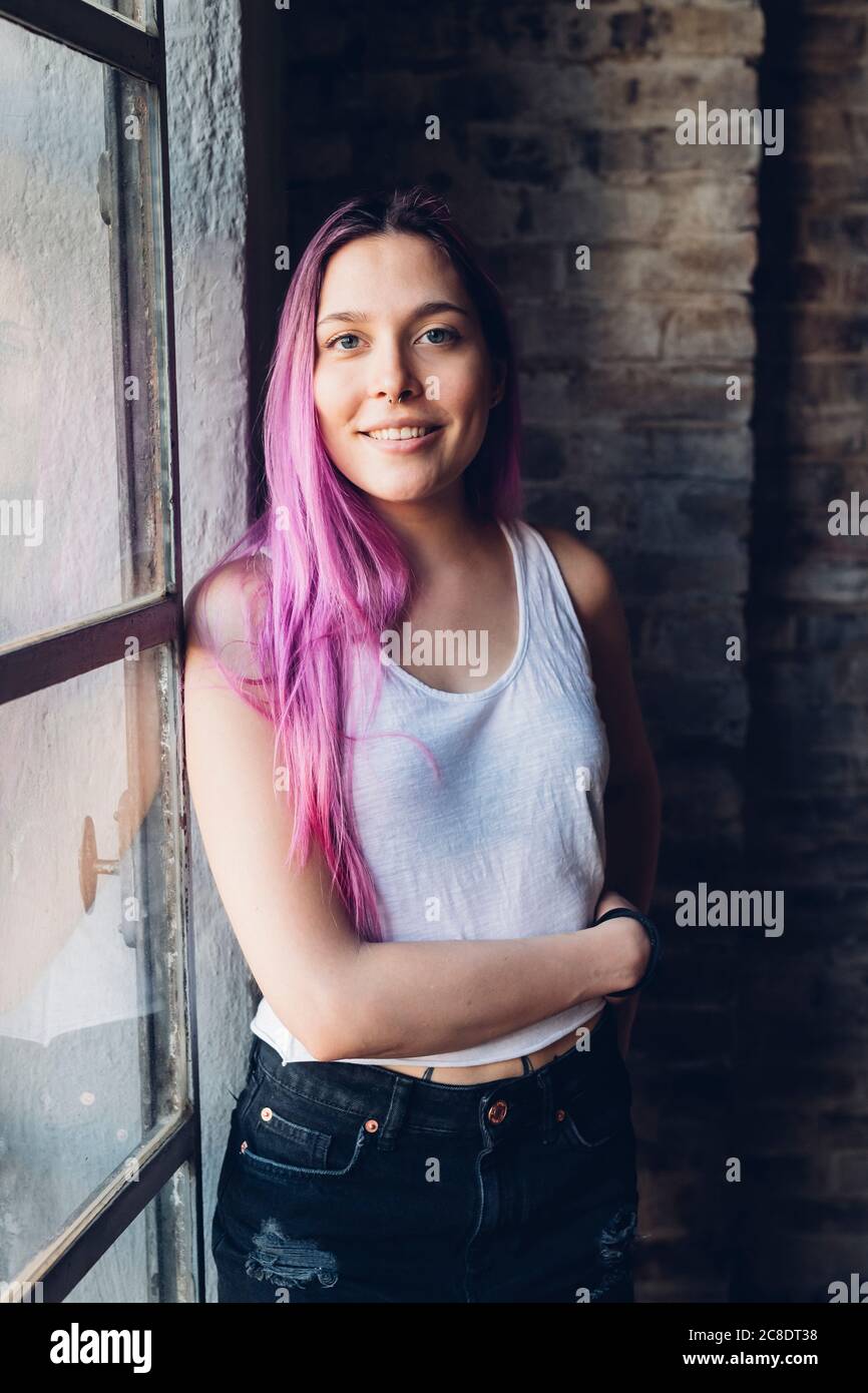 Portrait of a smiling young woman with pink hair in loft Stock Photo ...