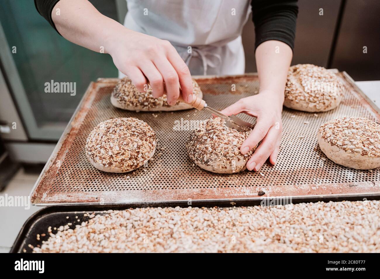 Baker cutting wholegrain buns at bakery Stock Photo - Alamy