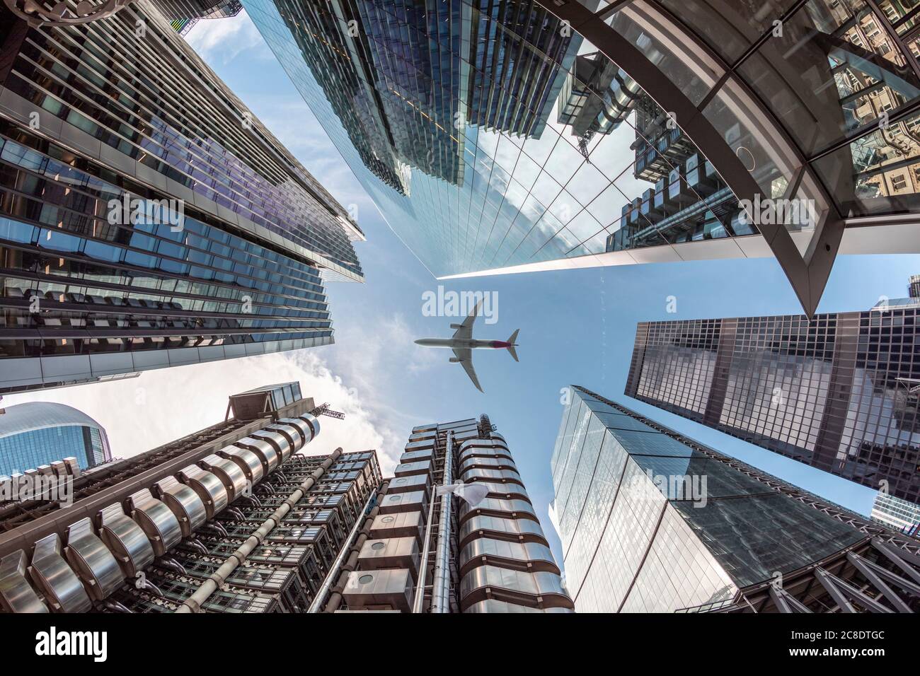 UK, London, Airplane flying over modern skyscrapers on a sunny day ...