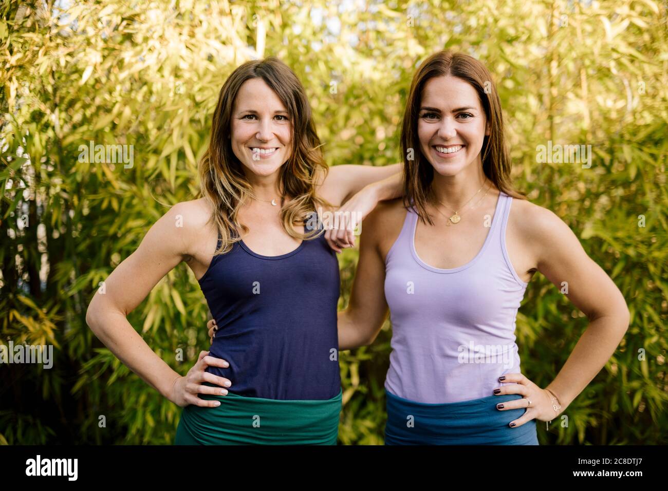 Smiling young friends standing against plants Stock Photo - Alamy