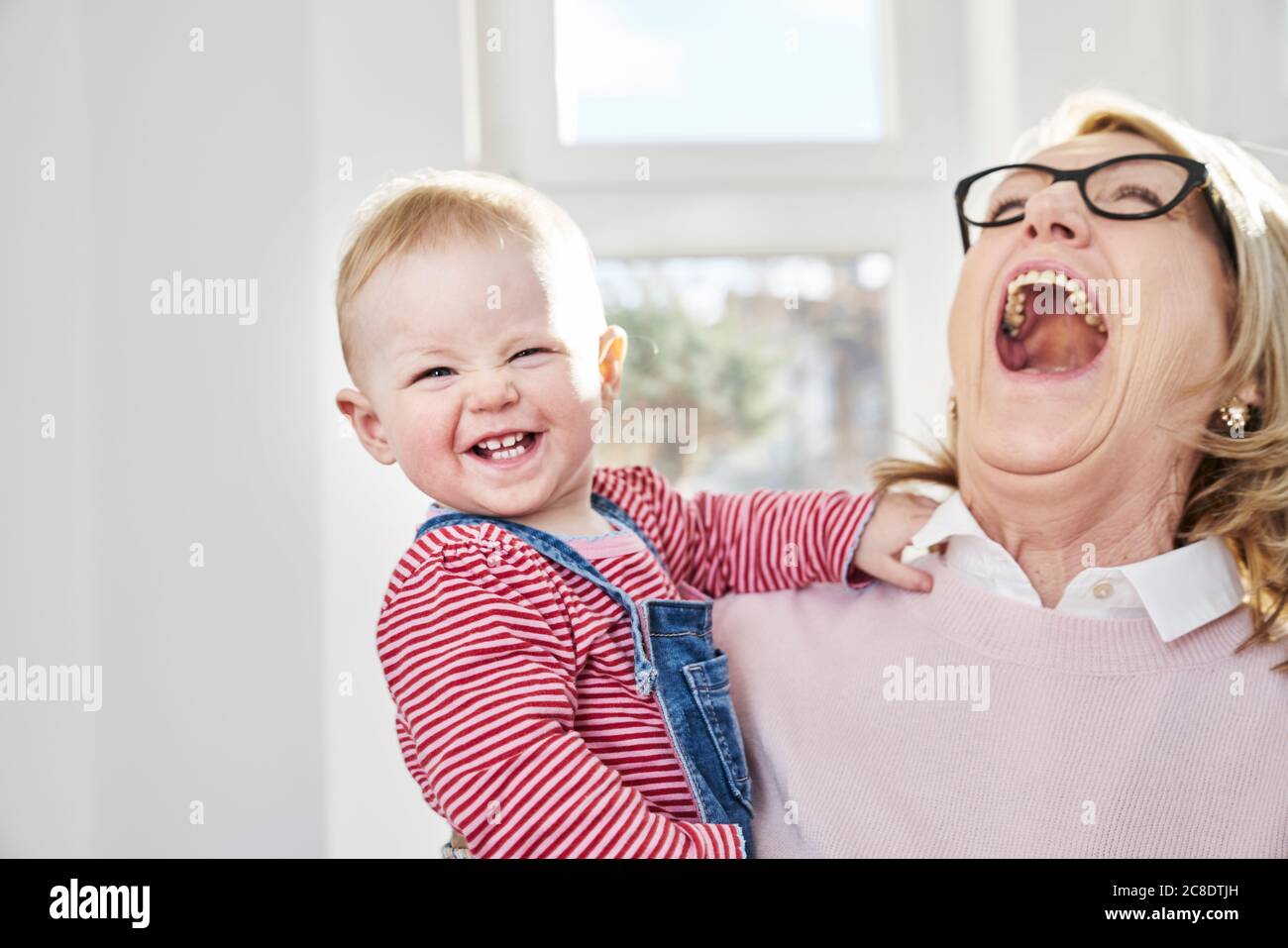 Happy grandmother carrying baby girl at home Stock Photo - Alamy