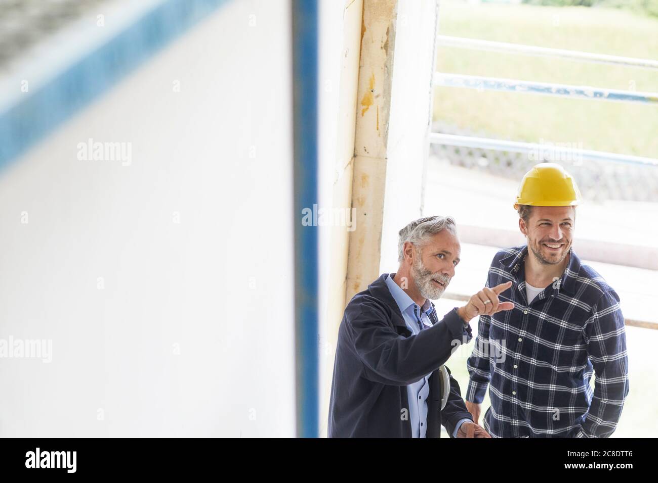 Architect and worker talking on a construction site Stock Photo - Alamy