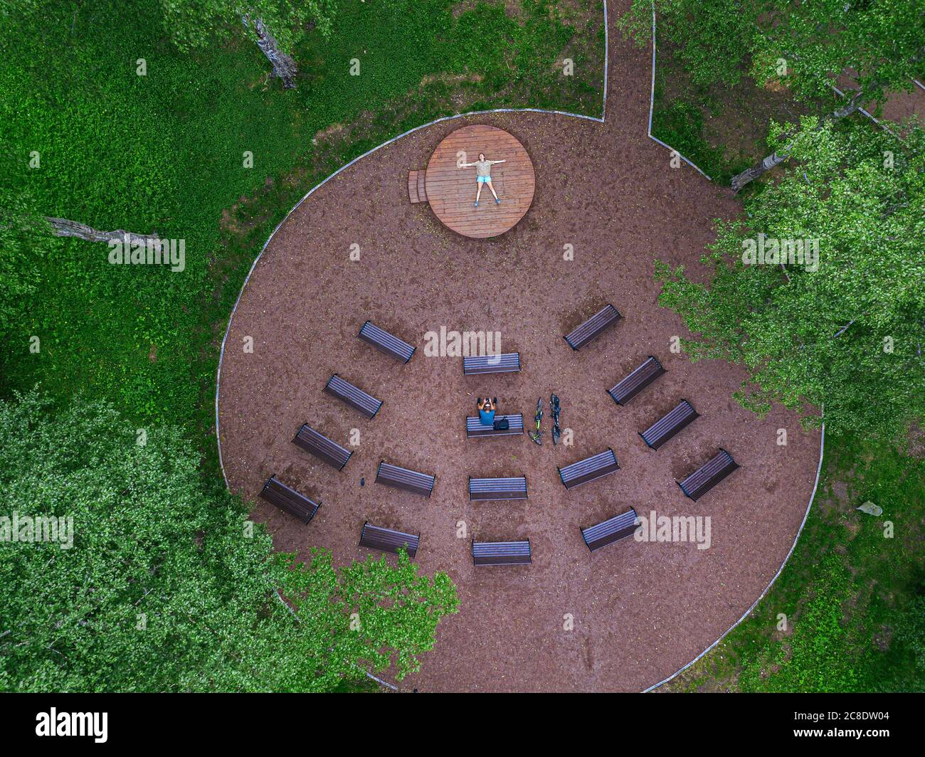 Aerial view of man sitting on bench while woman lying over wooden stage ...