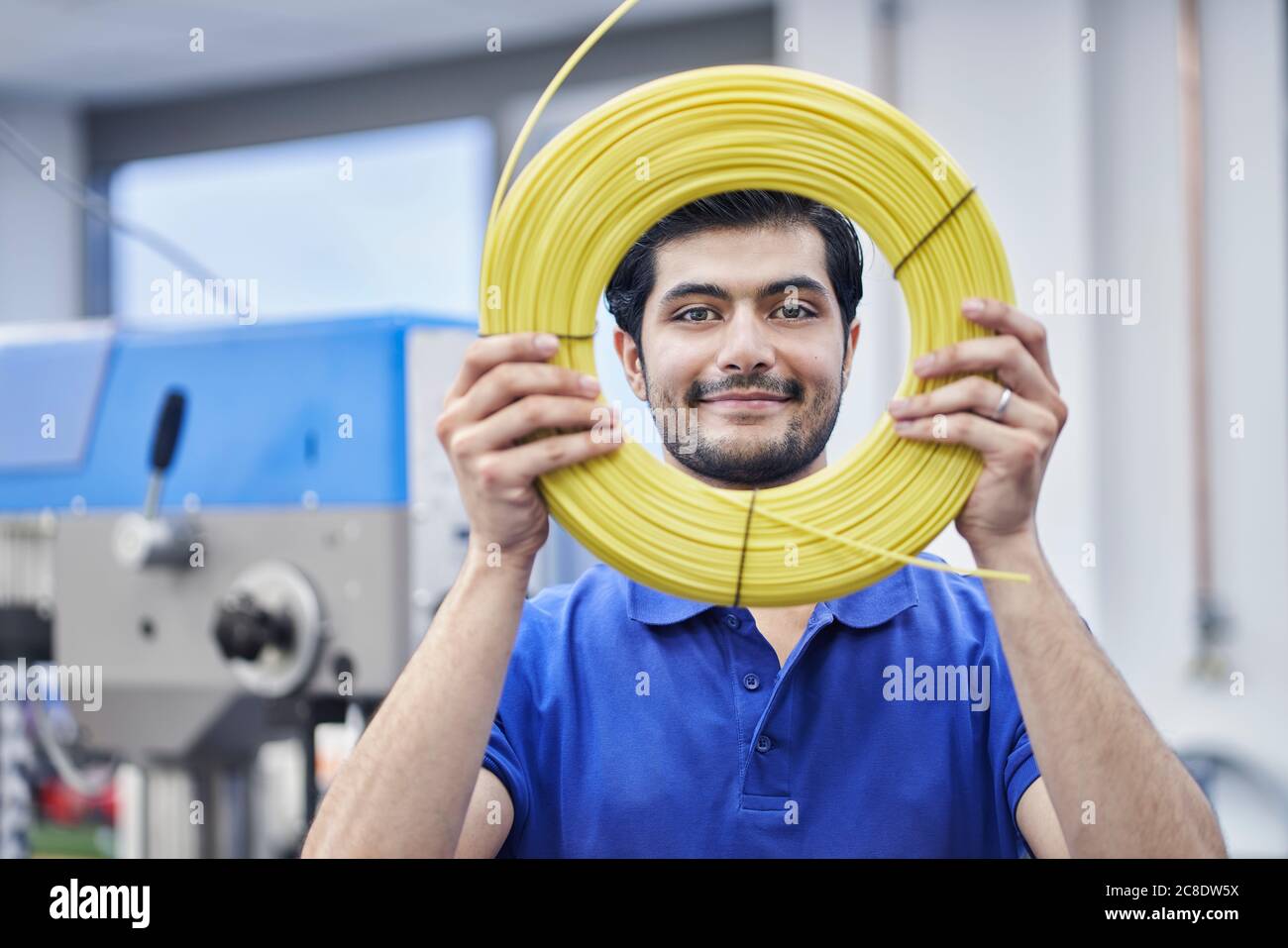 Confident male worker looking through rolled up cables in factory Stock ...