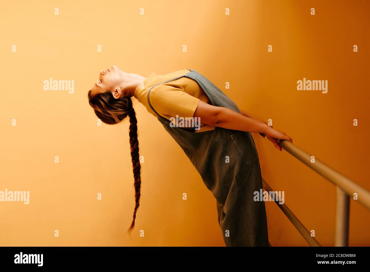 Young woman bending backwards in front of orange wall Stock Photo - Alamy