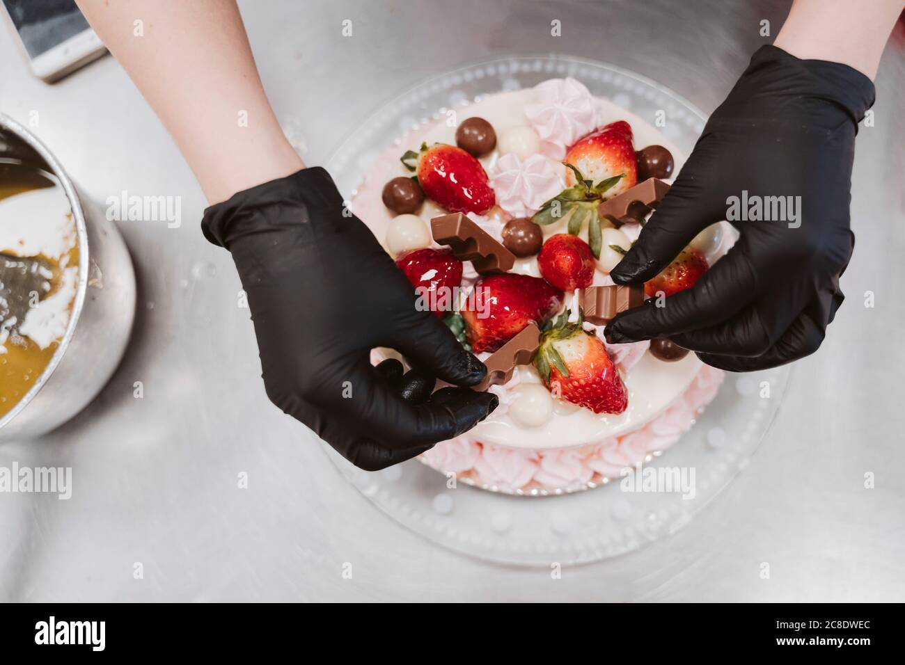 Female baker decorating cake on table in bakery Stock Photo - Alamy