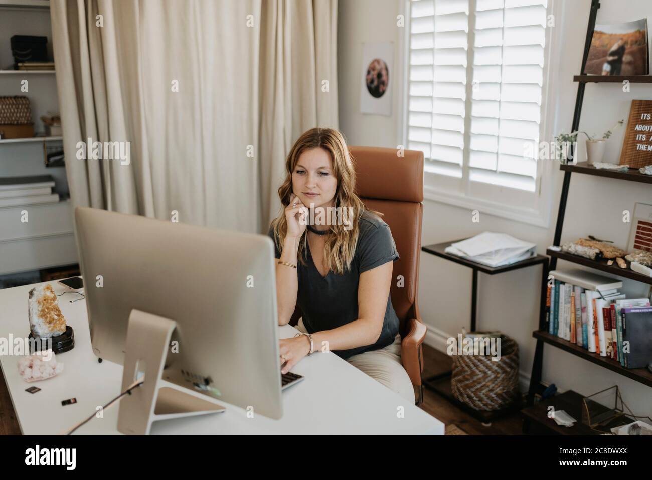 Mid adult woman using computer on desk at home Stock Photo - Alamy