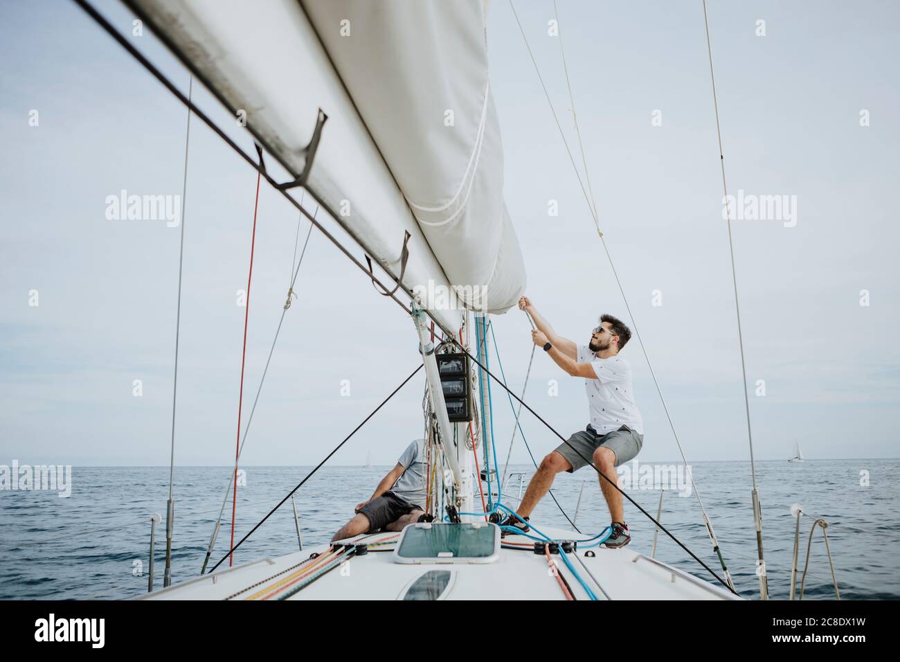 Sailor maneuvering setting the mainsail in sailboat against sky Stock ...