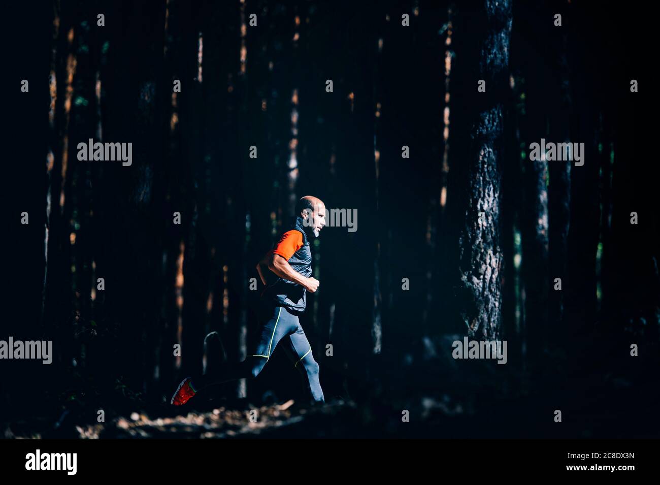 Mature man running against trees in forest Stock Photo - Alamy