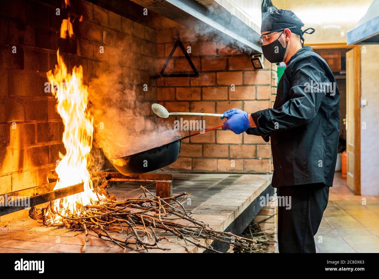 Traditional cooking of paella in restaurant kitchen, chef wearing ...