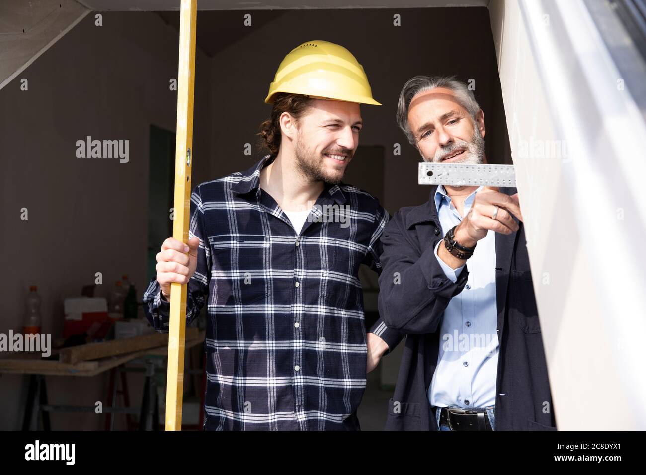 Smiling construction worker looking at measurement showing by architect ...