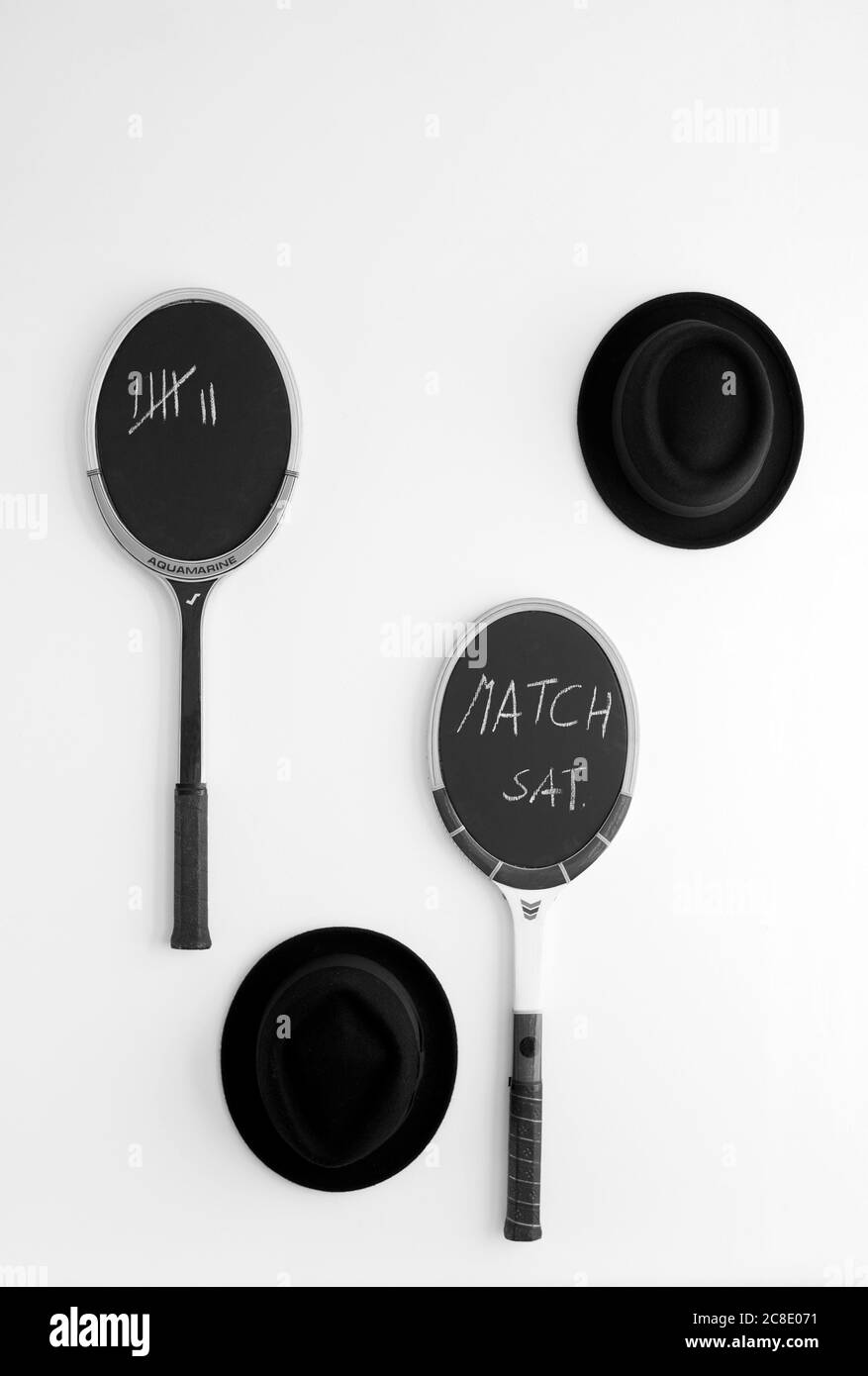 Black hats and blackboards made from tennis rackets hanging on white ...