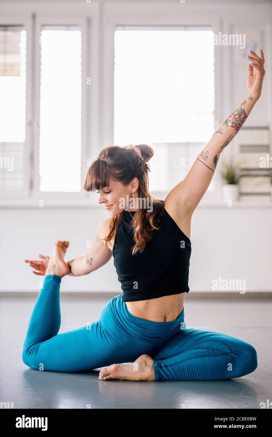 Female ballerina doing stretching exercises on floor in dance studio ...