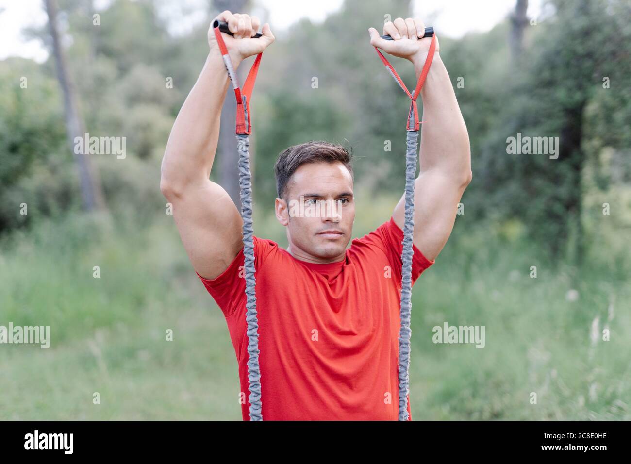 Man during workout with rubber rope in the woods Stock Photo - Alamy