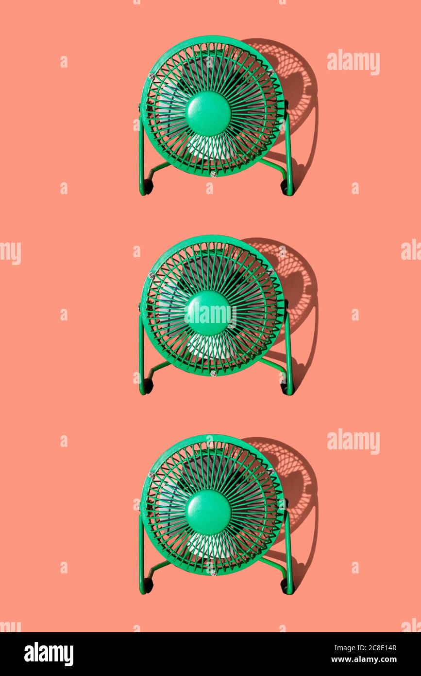 Green electric fans against orange background Stock Photo - Alamy