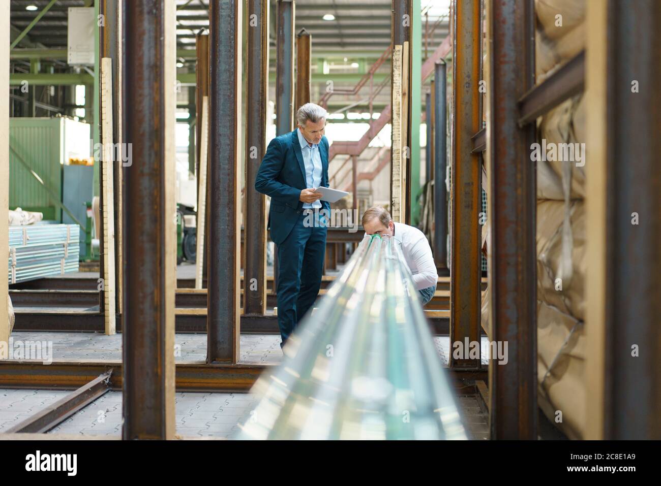 Two businessmen examining steel pipes in a factory Stock Photo - Alamy