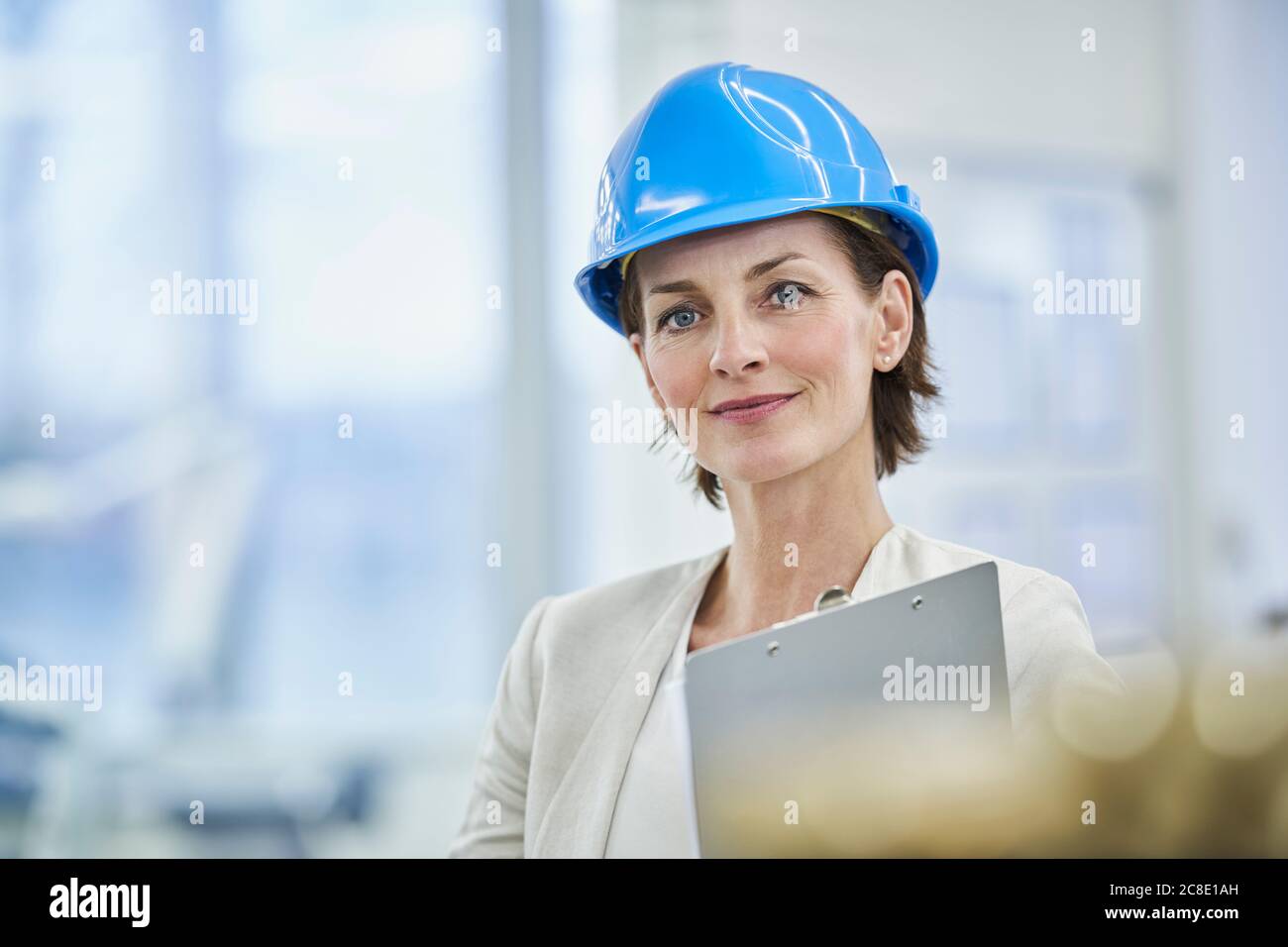 Confident female manager wearing blue hardhat in factory Stock Photo ...