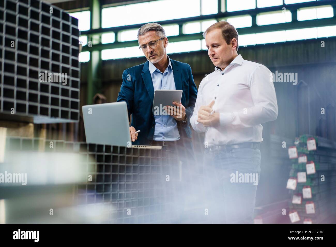 Two businessmen having a meeting in a factory using laptop Stock Photo ...