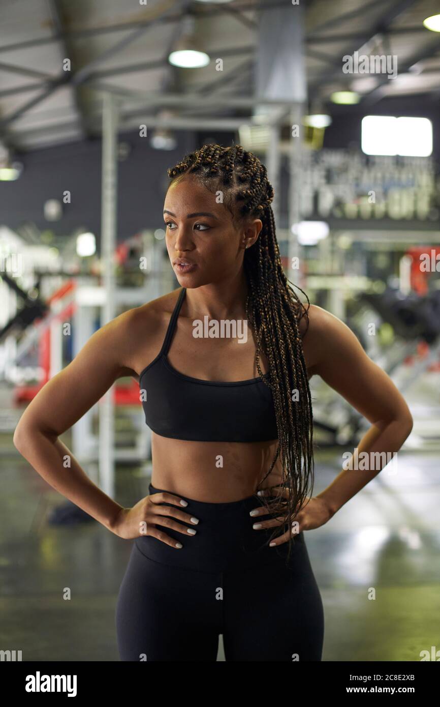 Confident female athlete with arms akimbo standing in gym Stock Photo ...