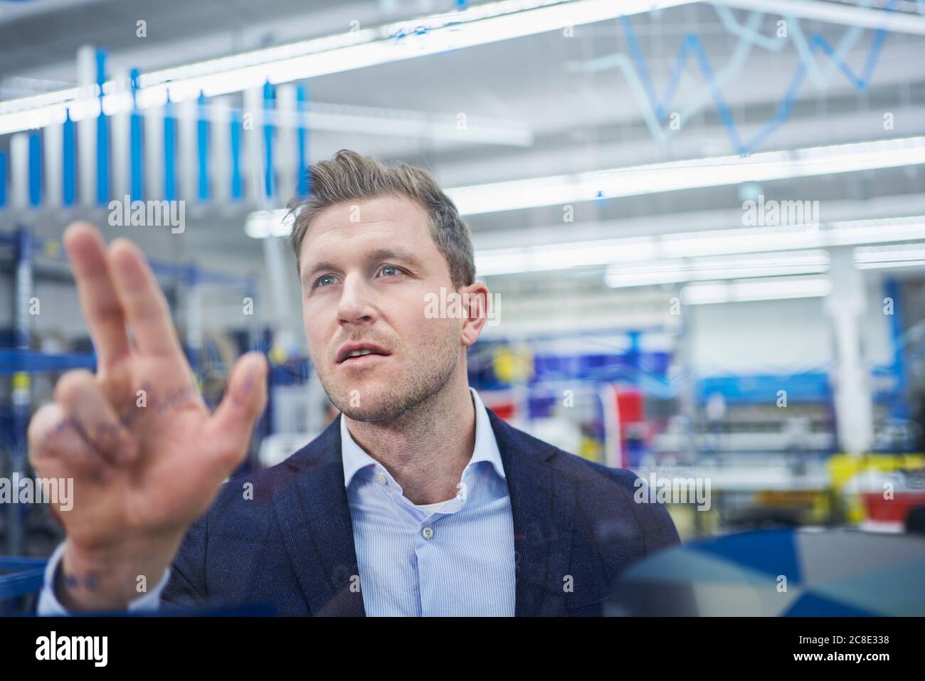 Male supervisor touching graphs on glass in factory Stock Photo - Alamy